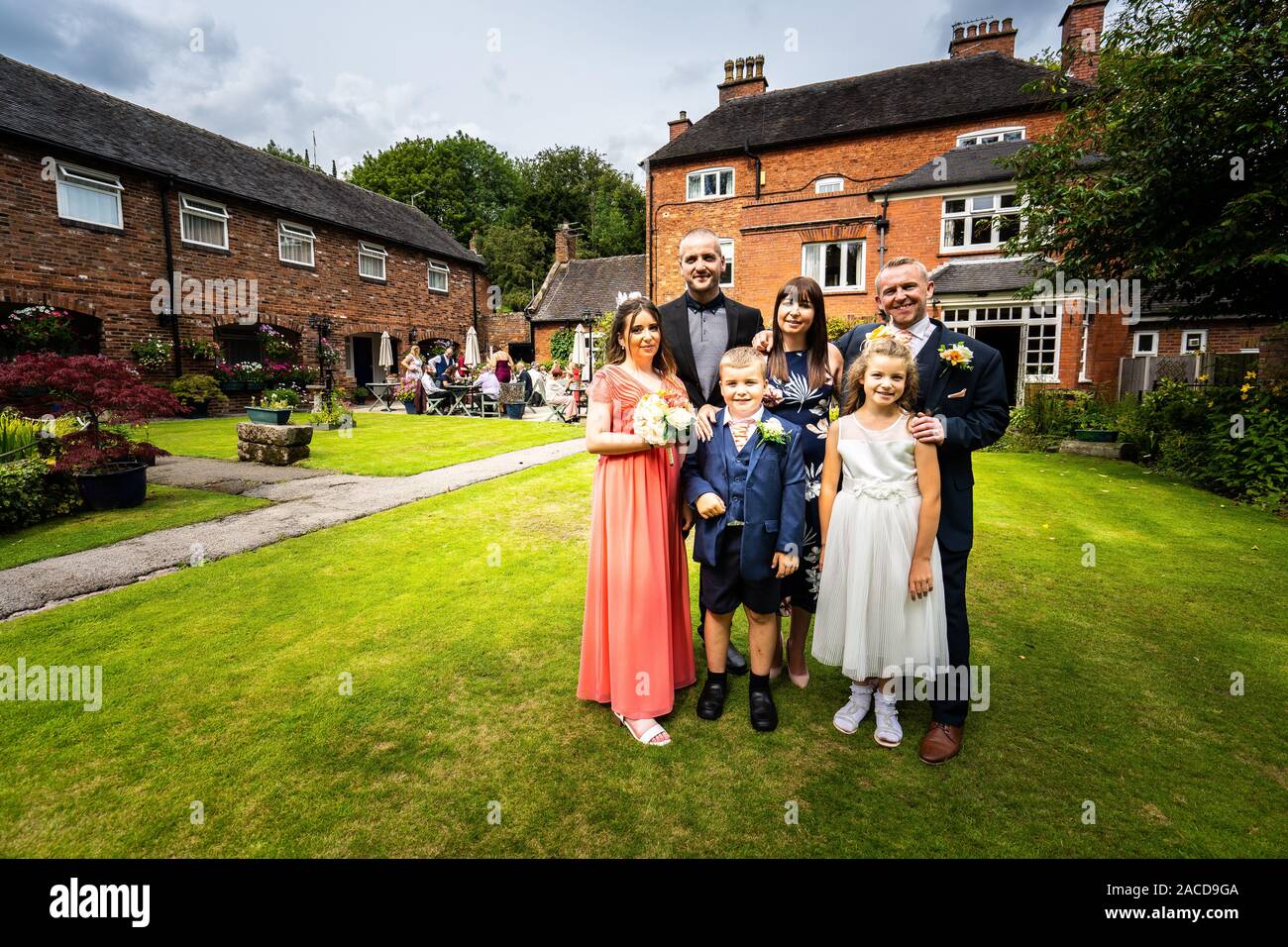 Bride, Groom and wedding guests pose for picture outside at the Manor ...