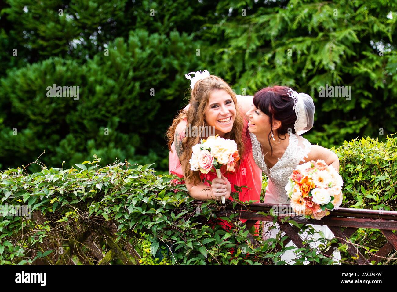 A bride and her maid of honour smiling, laughing and having fun on a ...