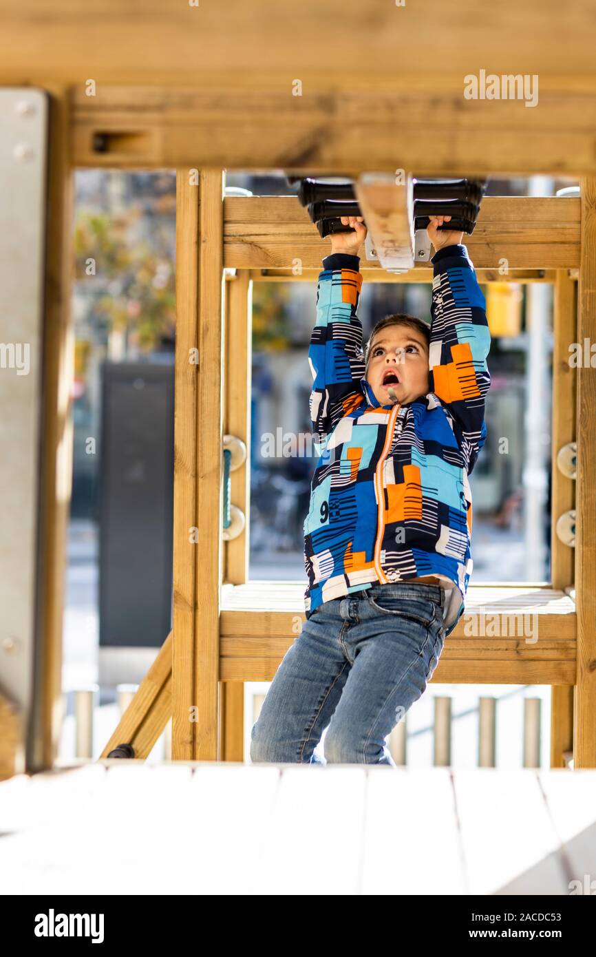 Little child scared hanging on a wooden playground Stock Photo - Alamy