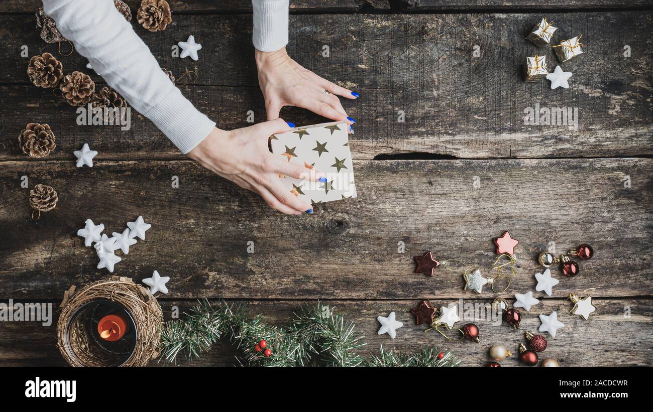 Top view of female hand closing a holiday gift box with golden stars in ...