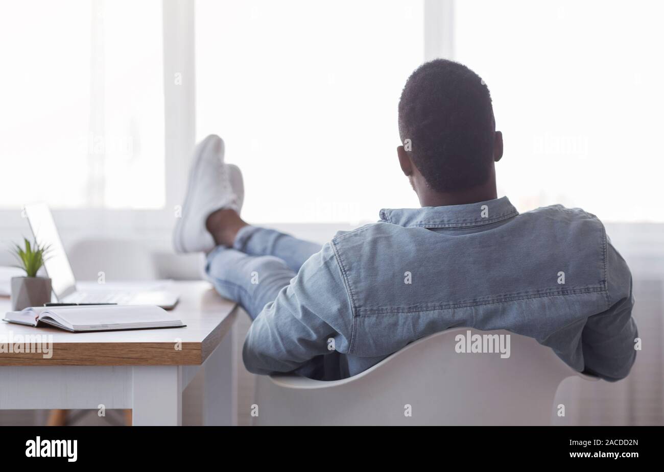 Lazy employee sitting with legs on desk and looking to window Stock ...