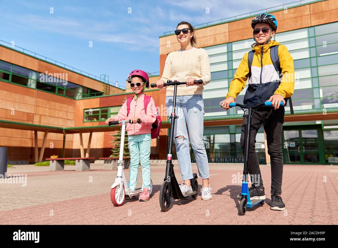 happy school children with mother riding scooters Stock Photo - Alamy