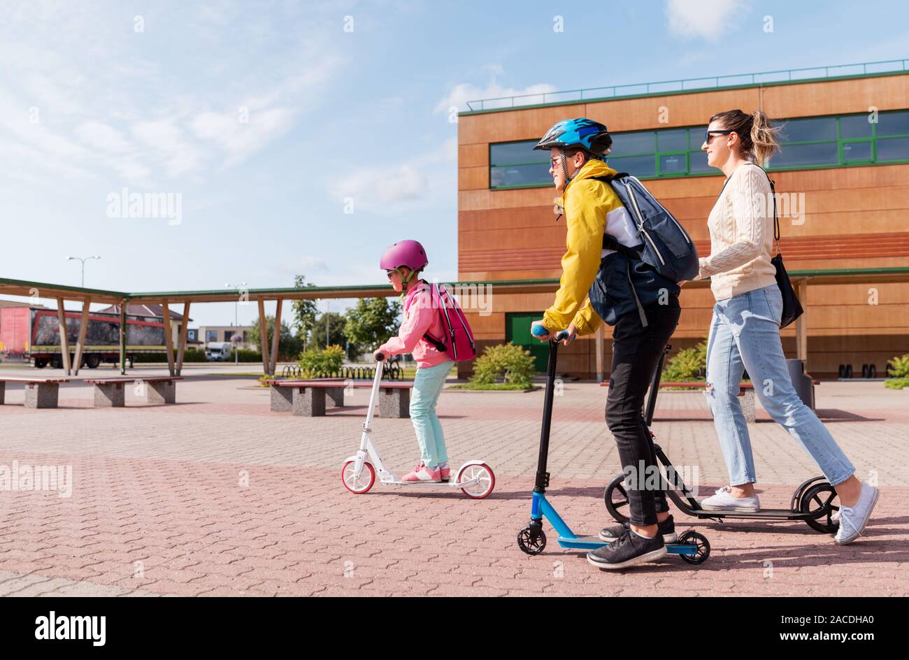 happy school children with mother riding scooters Stock Photo - Alamy