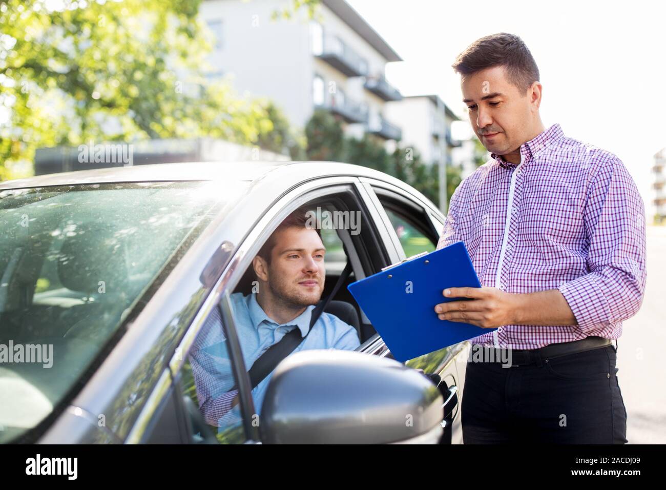 car driving instructor with clipboard and driver Stock Photo - Alamy