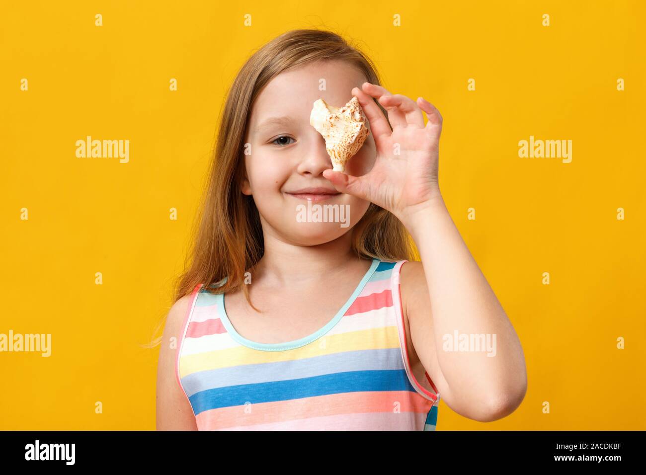 Little girl holding a seashell. Closeup baby in a summer dress on a ...