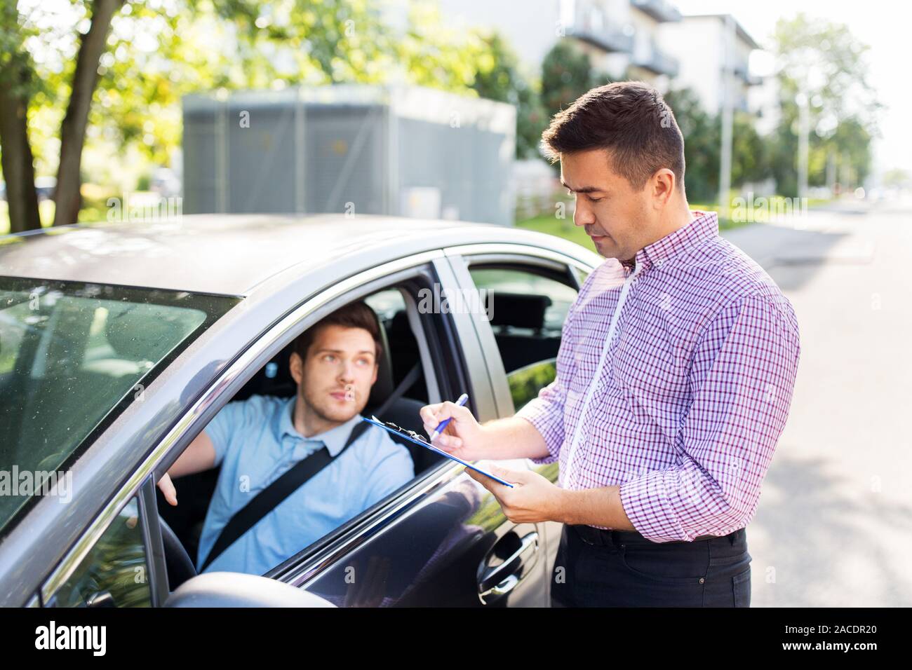 car driving instructor with clipboard and driver Stock Photo - Alamy