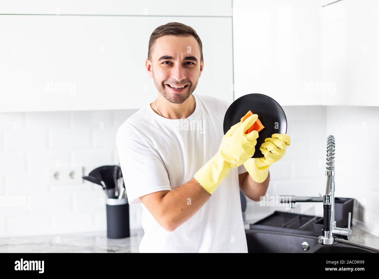 Smiling man washing dish in the kitchen Stock Photo - Alamy