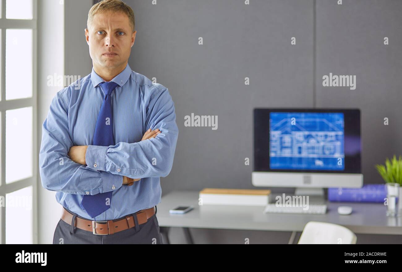 Happy businessman standing behind office desk, smiling Stock Photo - Alamy
