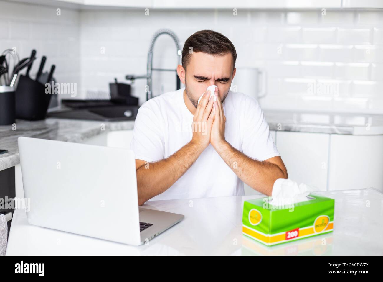 Young man sick man sneeze nose working on laptop in the kitchen Stock ...
