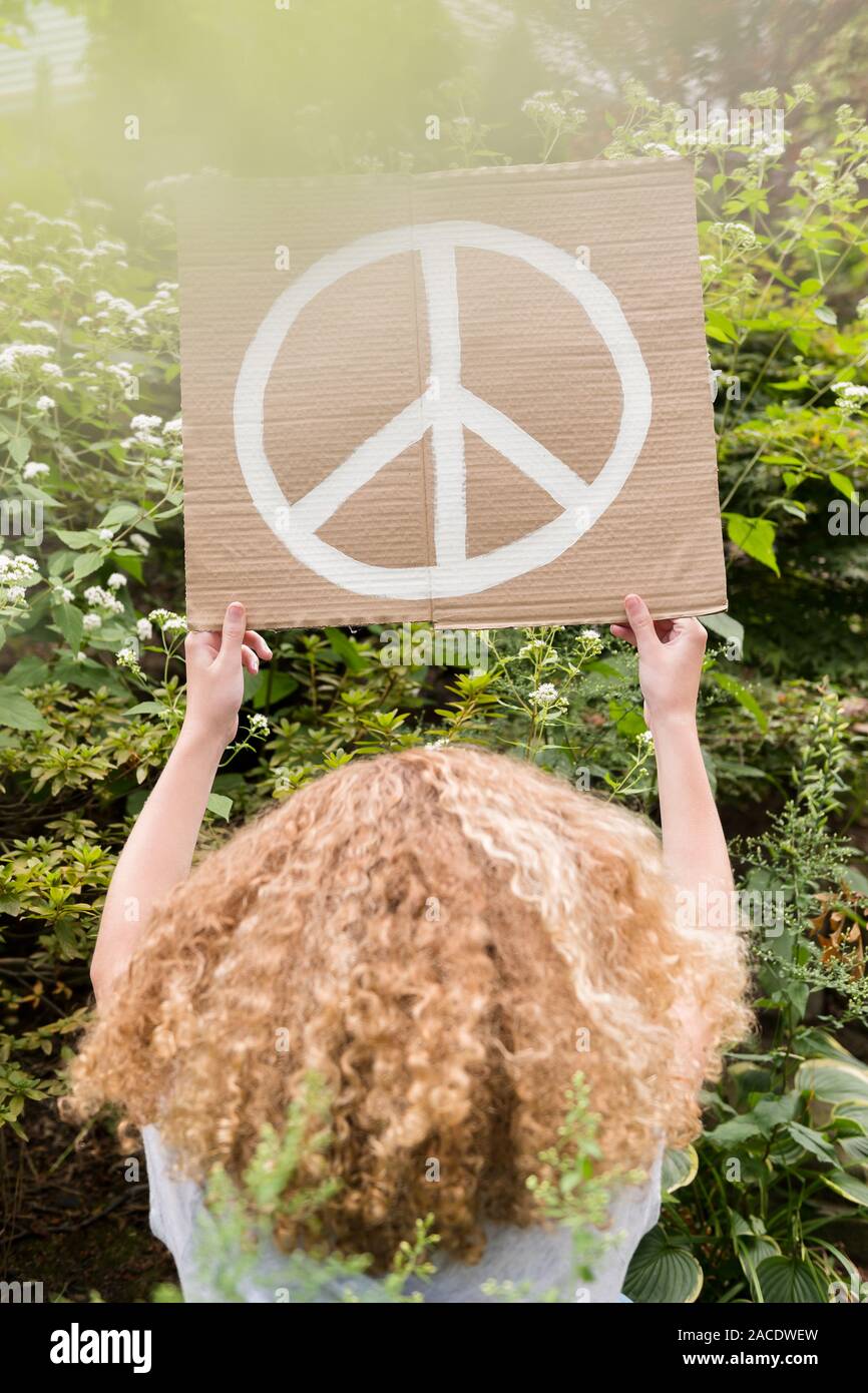 Girl holding sign with peace symbol Stock Photo - Alamy
