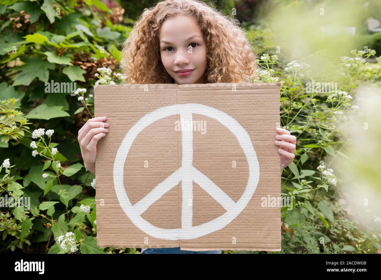 Girl holding sign with peace symbol Stock Photo - Alamy