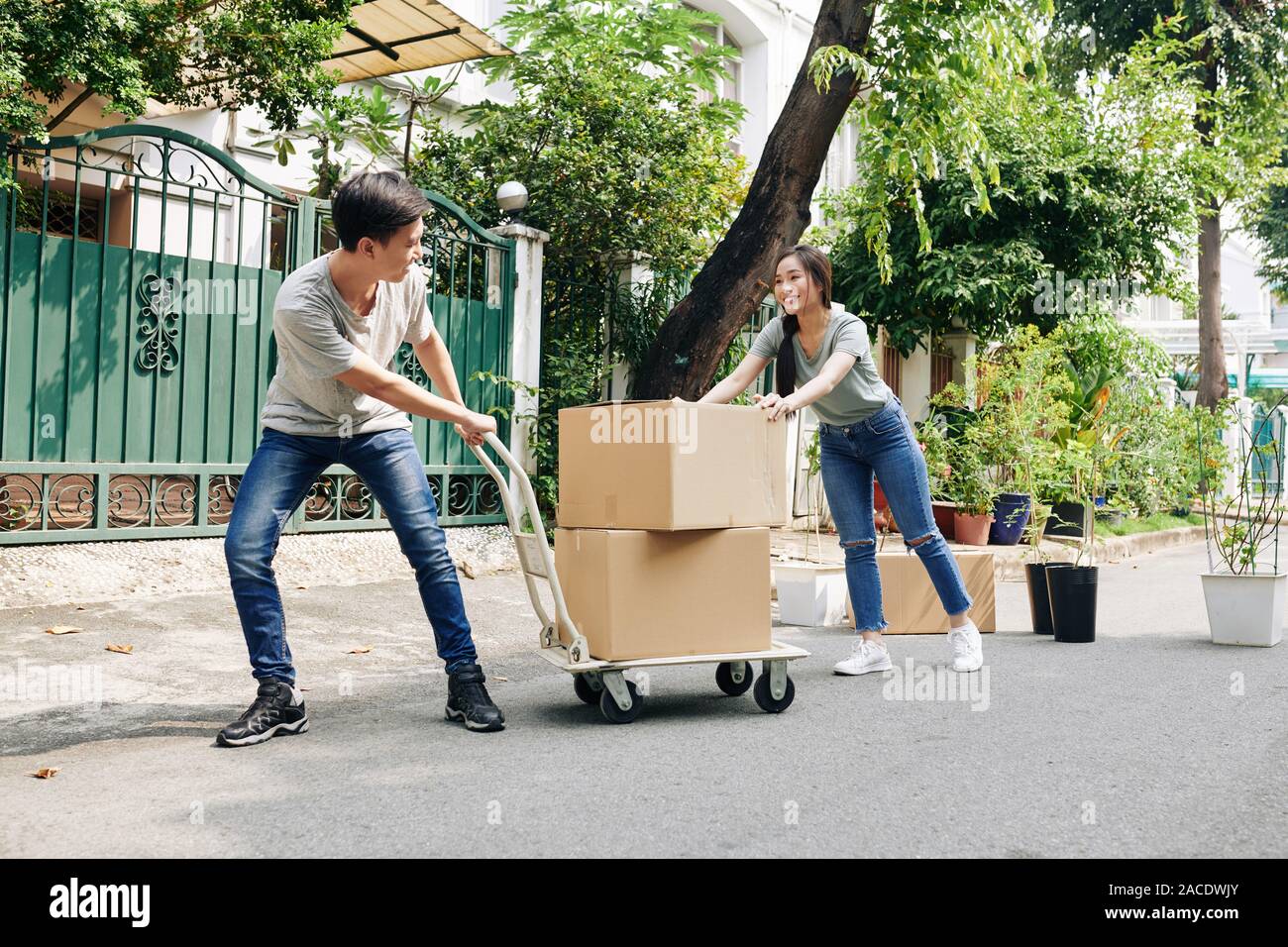 Young Vietnamese couple using trolley cart when moving in new house and ...