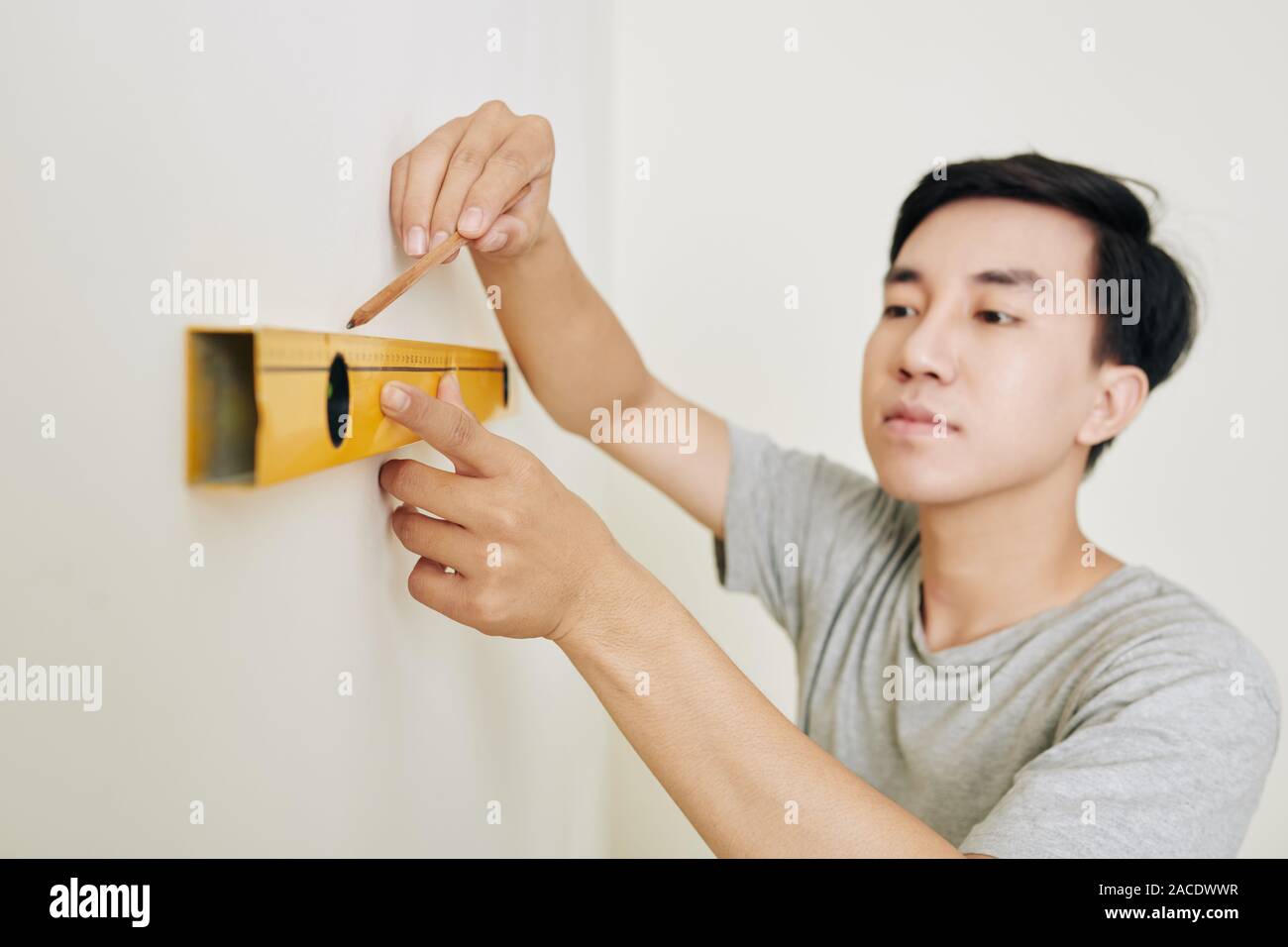 Handsome young Vietnamese man using spirit level when drawing stright ...