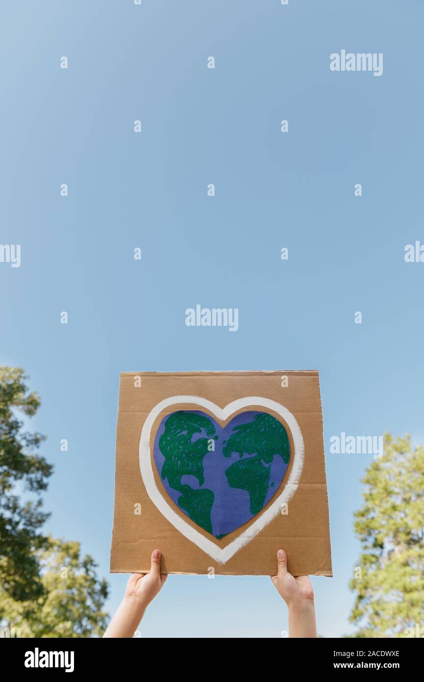 Young environmental activist holding sign against blue sky Stock Photo ...