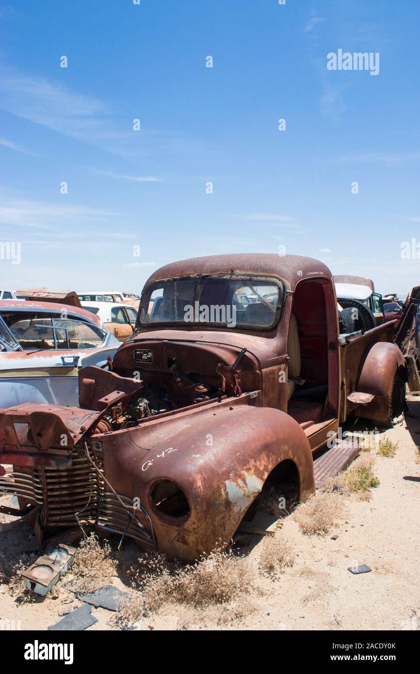 abandoned rusty cars and trucks in a junk yard in the desert near ...