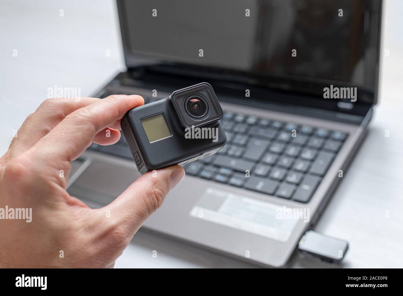 Action camera in hand. Laptop in background. Concept of transferring ...
