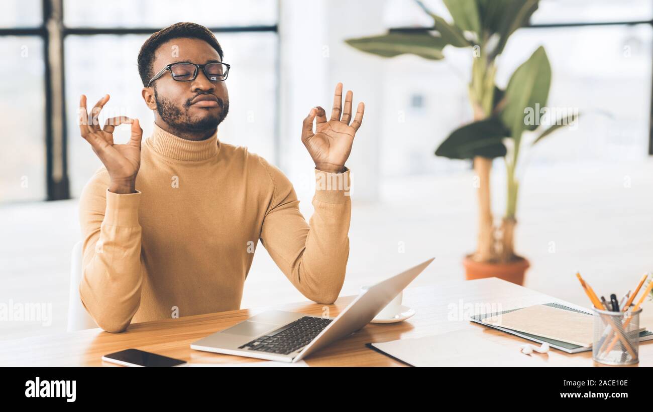Calm black guy meditating while doing homework Stock Photo - Alamy
