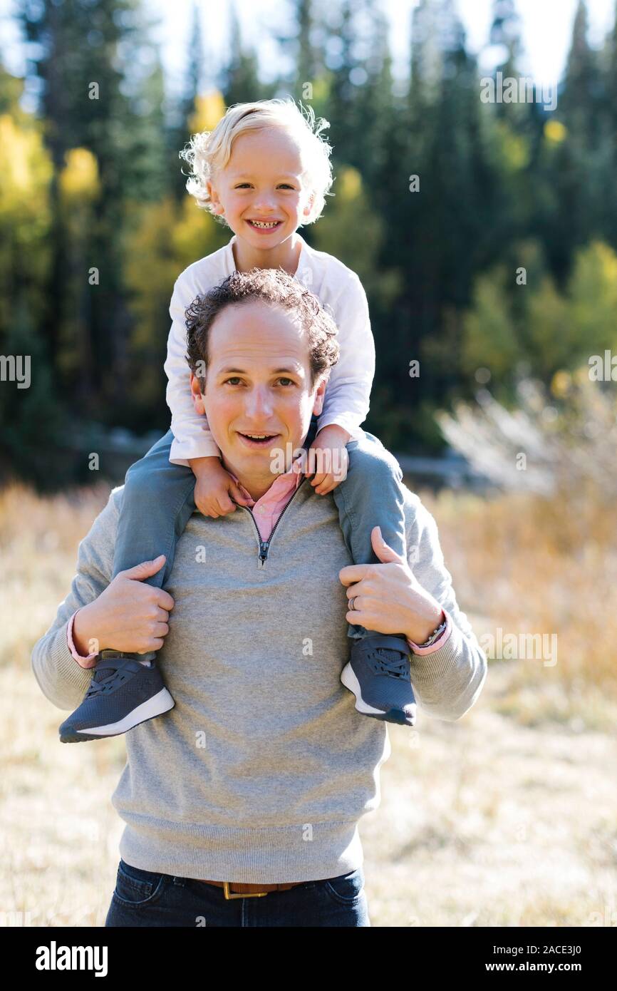Son sitting on father's shoulders in nature Stock Photo - Alamy