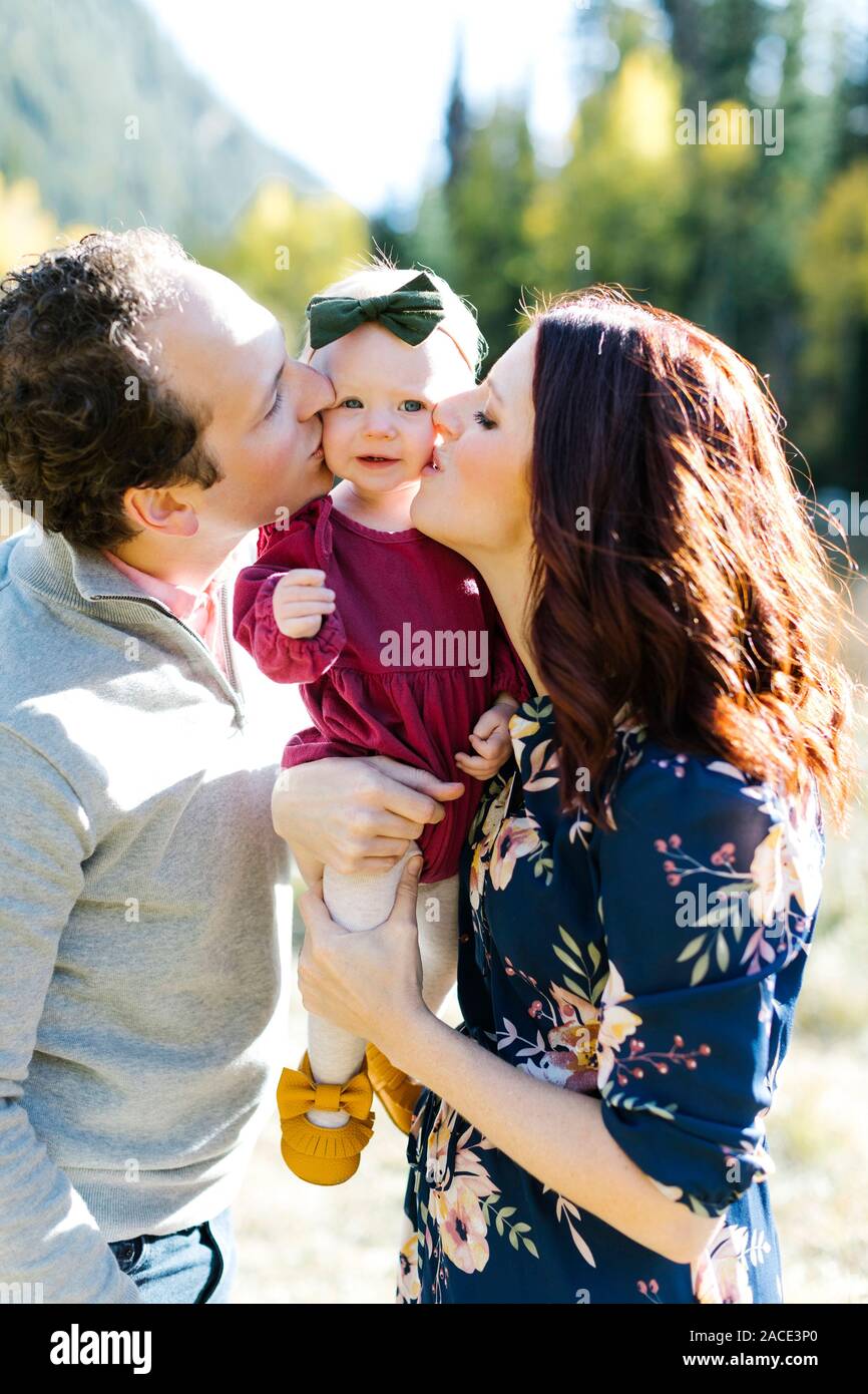Parents kissing daughter in nature Stock Photo - Alamy