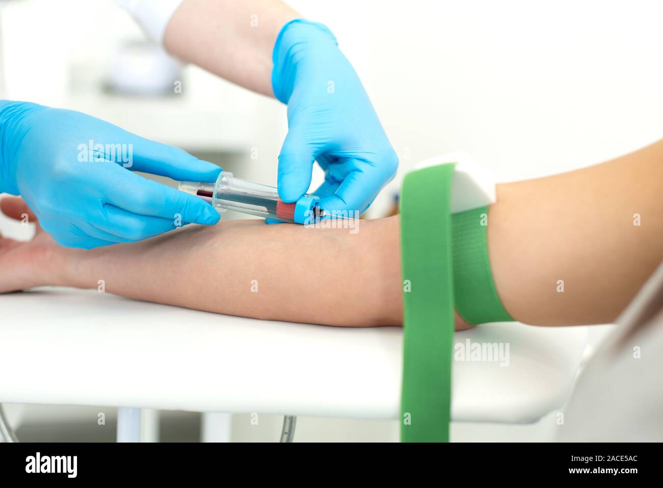 a gloved nurse inserts a needle into a vein on the patient arm and ...