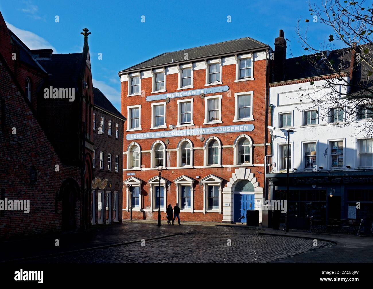 Couple walking past old warehouse and Trinity Square, Hull, East ...