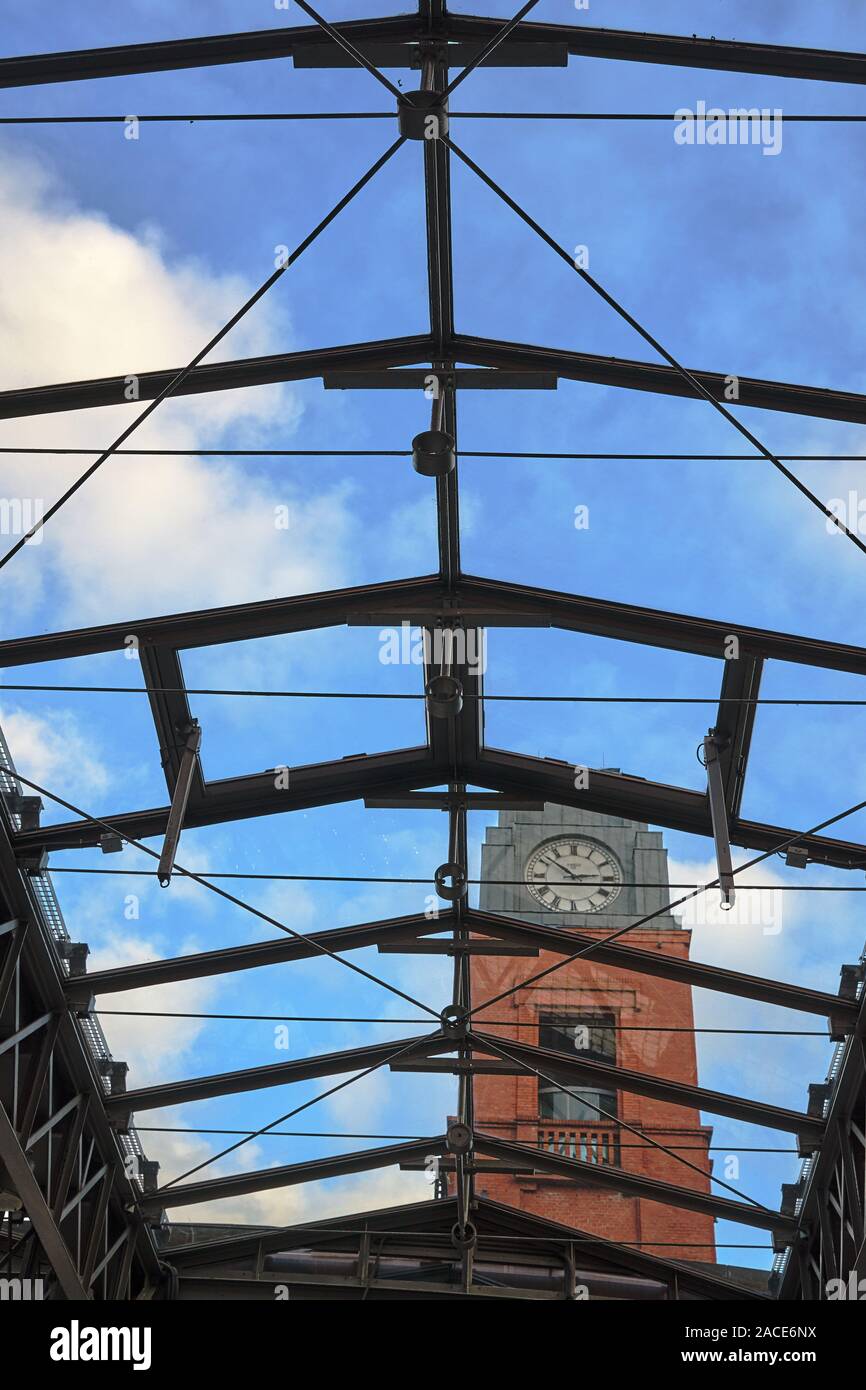 The structure of the glass roof and the red brick clock tower at the ...