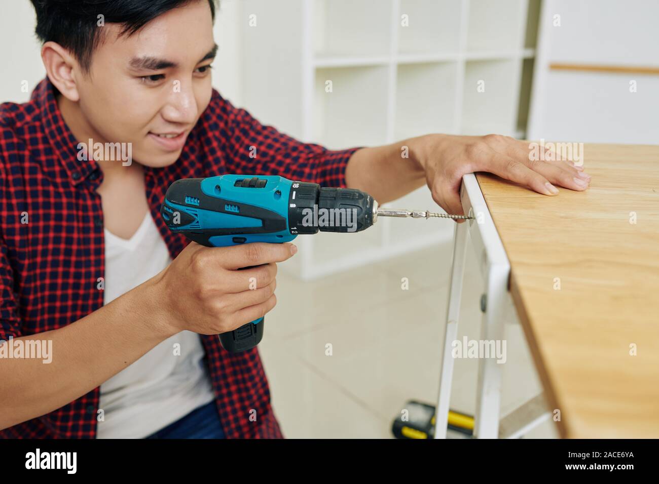 Positive excited handsome young Asian man using screwdriver for fixing ...