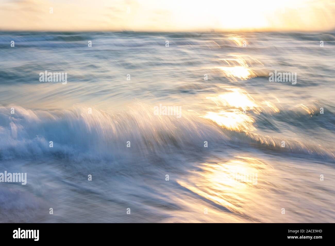 Blurred image of sun reflecting on waves Stock Photo - Alamy