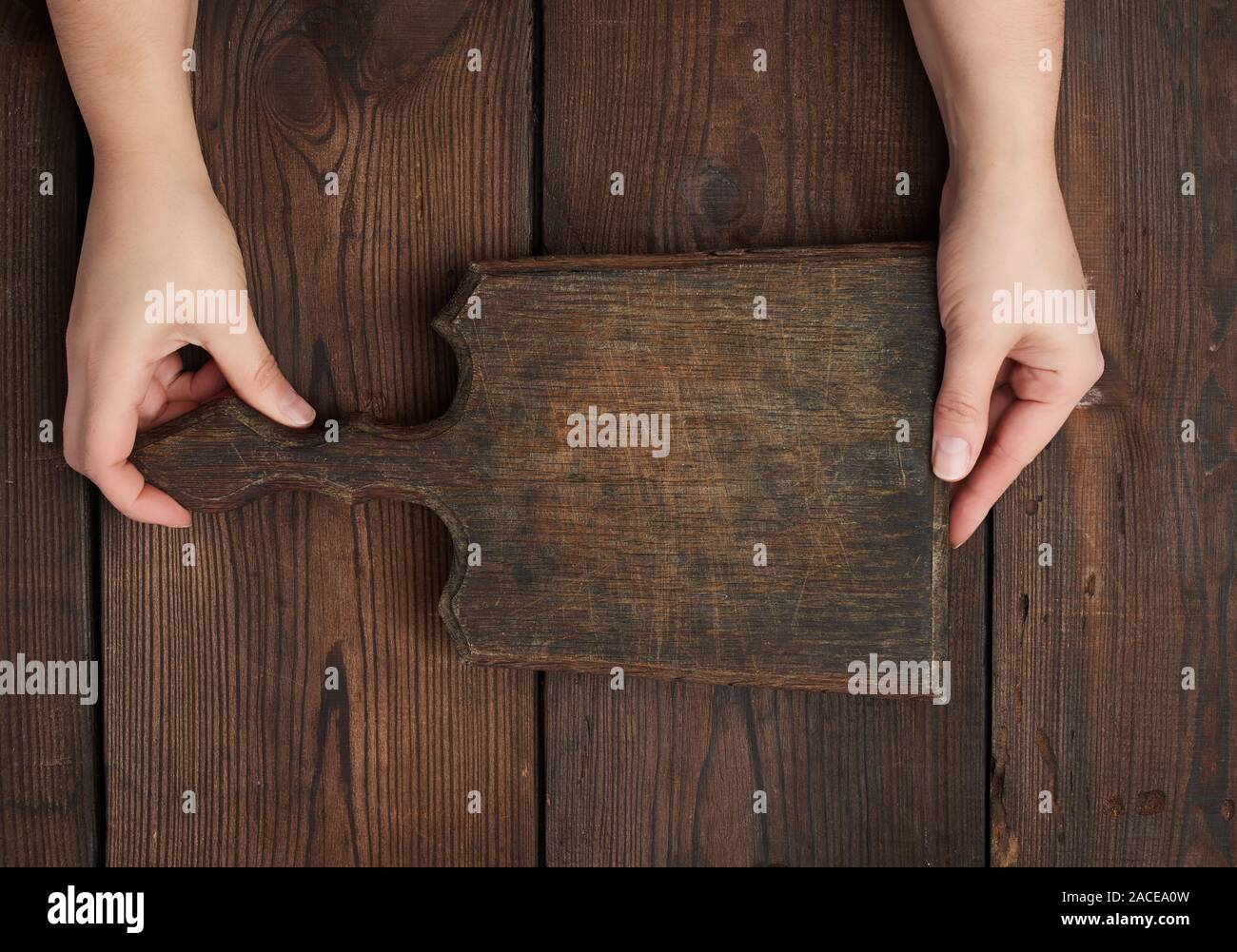 two hands holding a vintage brown empty kitchen cutting board with a ...