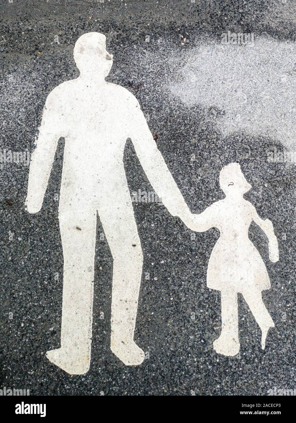 White paint of adult and child walking hand in hand on black asphalt ...