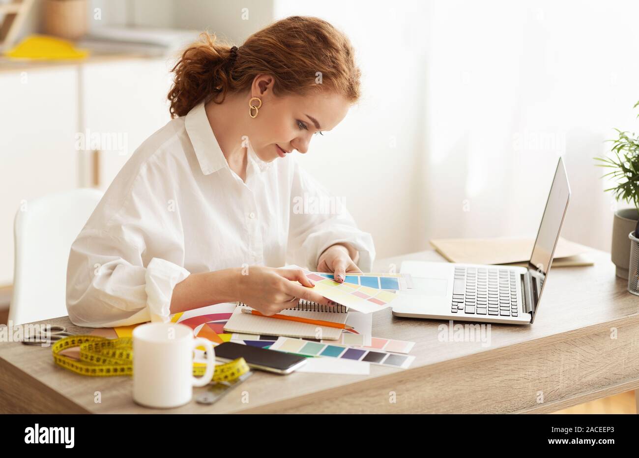 Designer atelier. Dressmaker choosing color samples for new collection ...