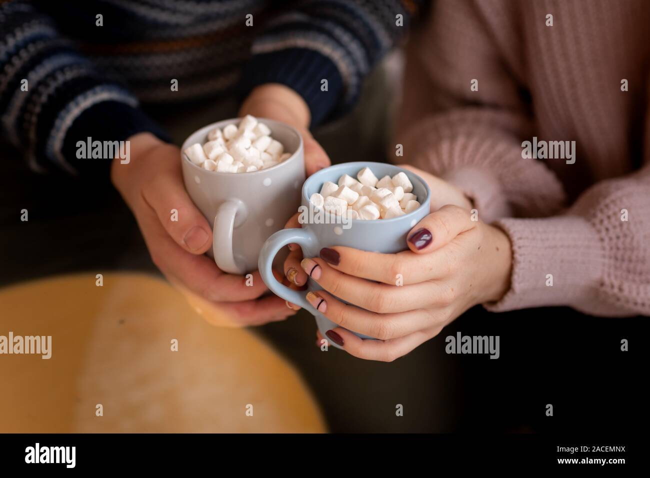 Happy couple's hands holding hot cups with hot drinks with marshmallow ...