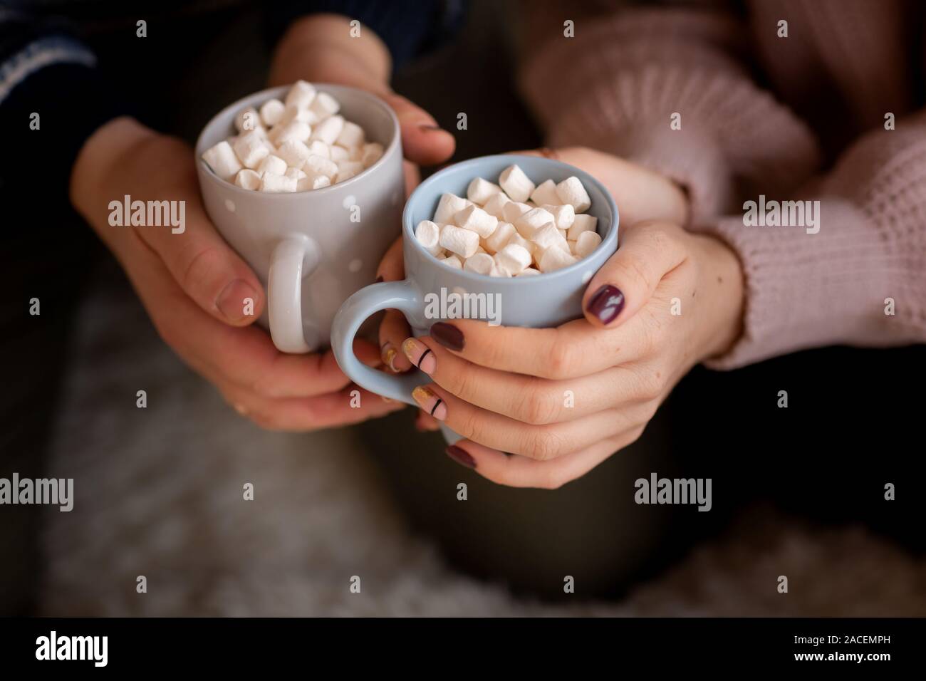 Happy couple's hands holding hot cups with hot drinks with marshmallow ...