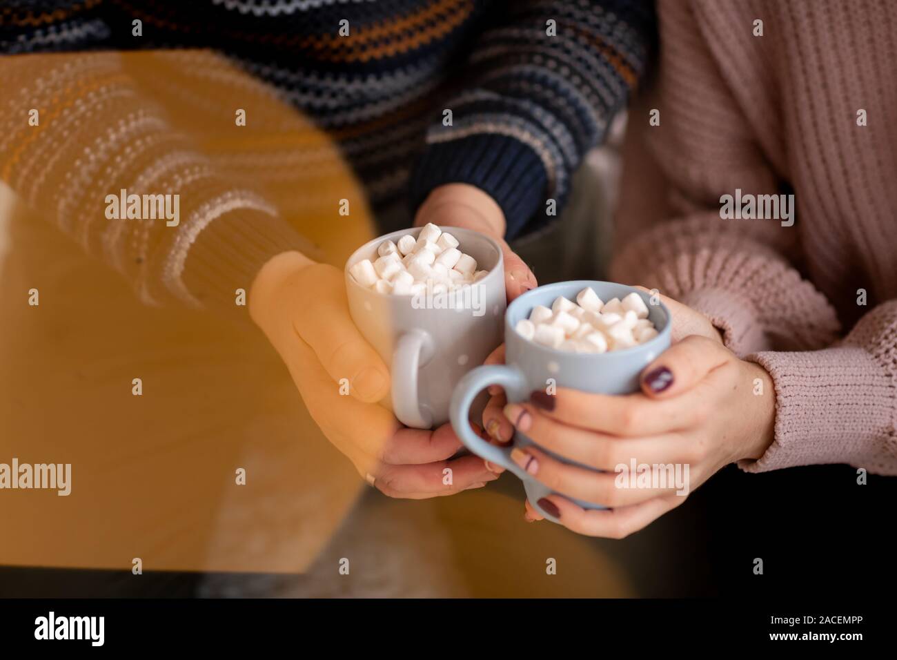 Happy couple's hands holding hot cups with hot drinks with marshmallow ...