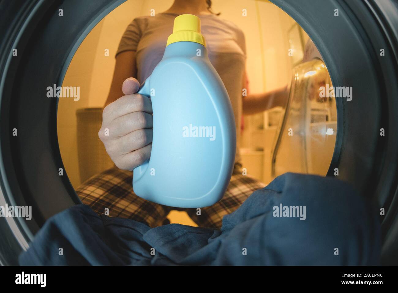 Woman pouring a detergent into washing machine. View from a drum of ...