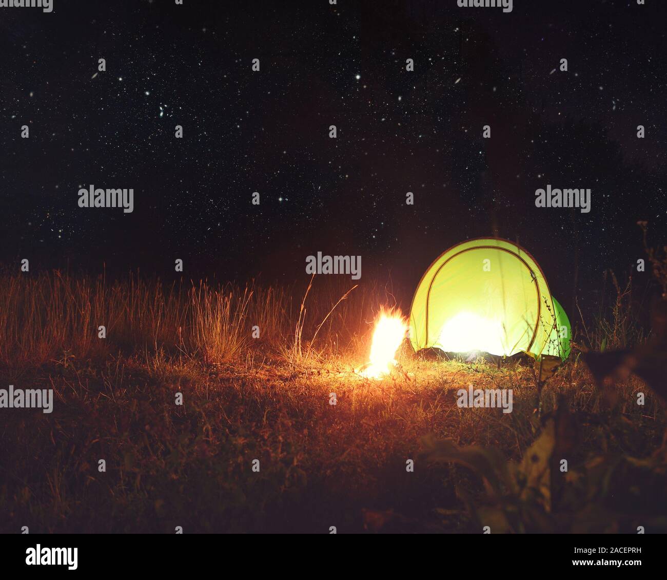 Green camping tent with bonfire in the forest at night under the stars ...