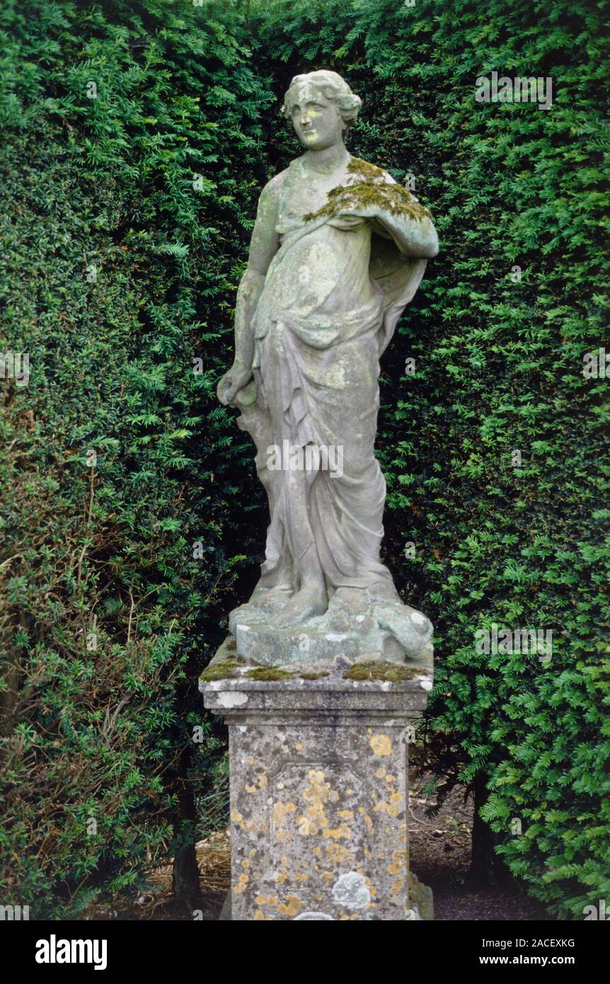 Statue in garden. Statue of classical female figure in front of hedge ...