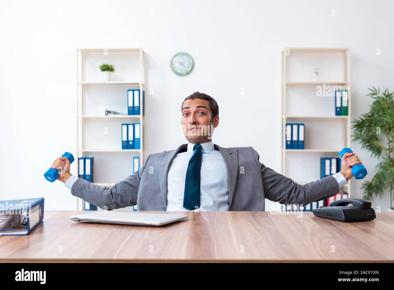 The young handsome employee doing sport exercises at workplace Stock ...