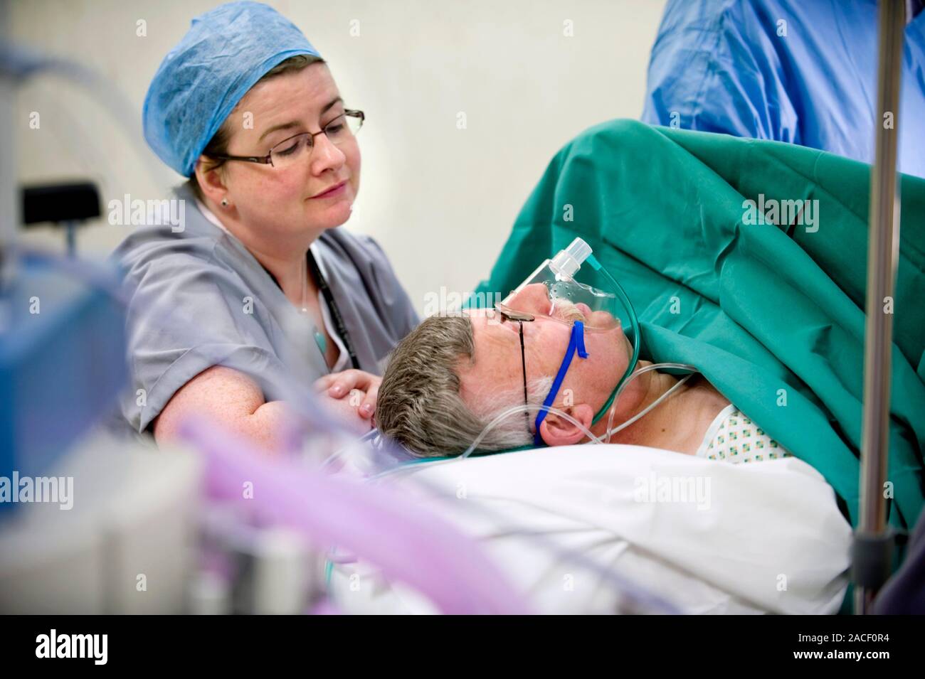 Hernia operation. Anaesthetist looking on as a patient undergoes ...