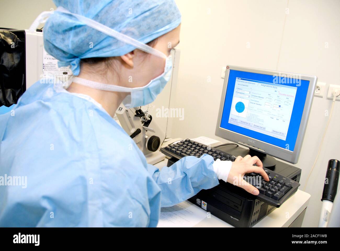 Laser eye surgery. Nurse using a computer to record information about a ...