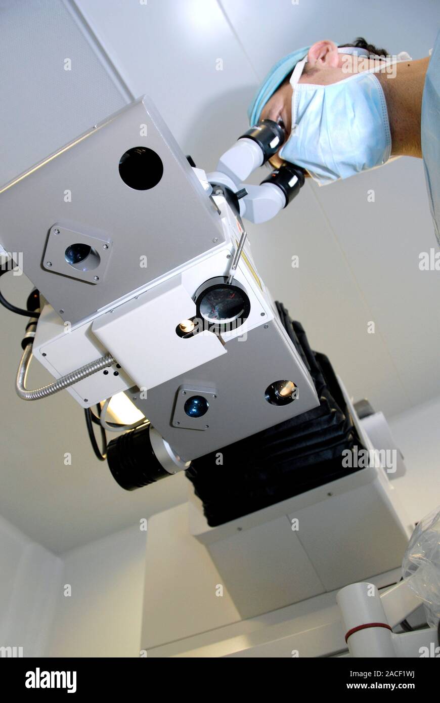 Laser eye surgery microscope. Surgeon using a microscope while carrying ...