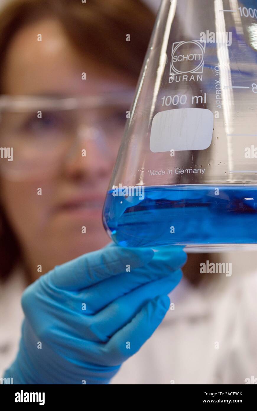 Chemistry experiment. Researcher holding a conical flask containing a ...