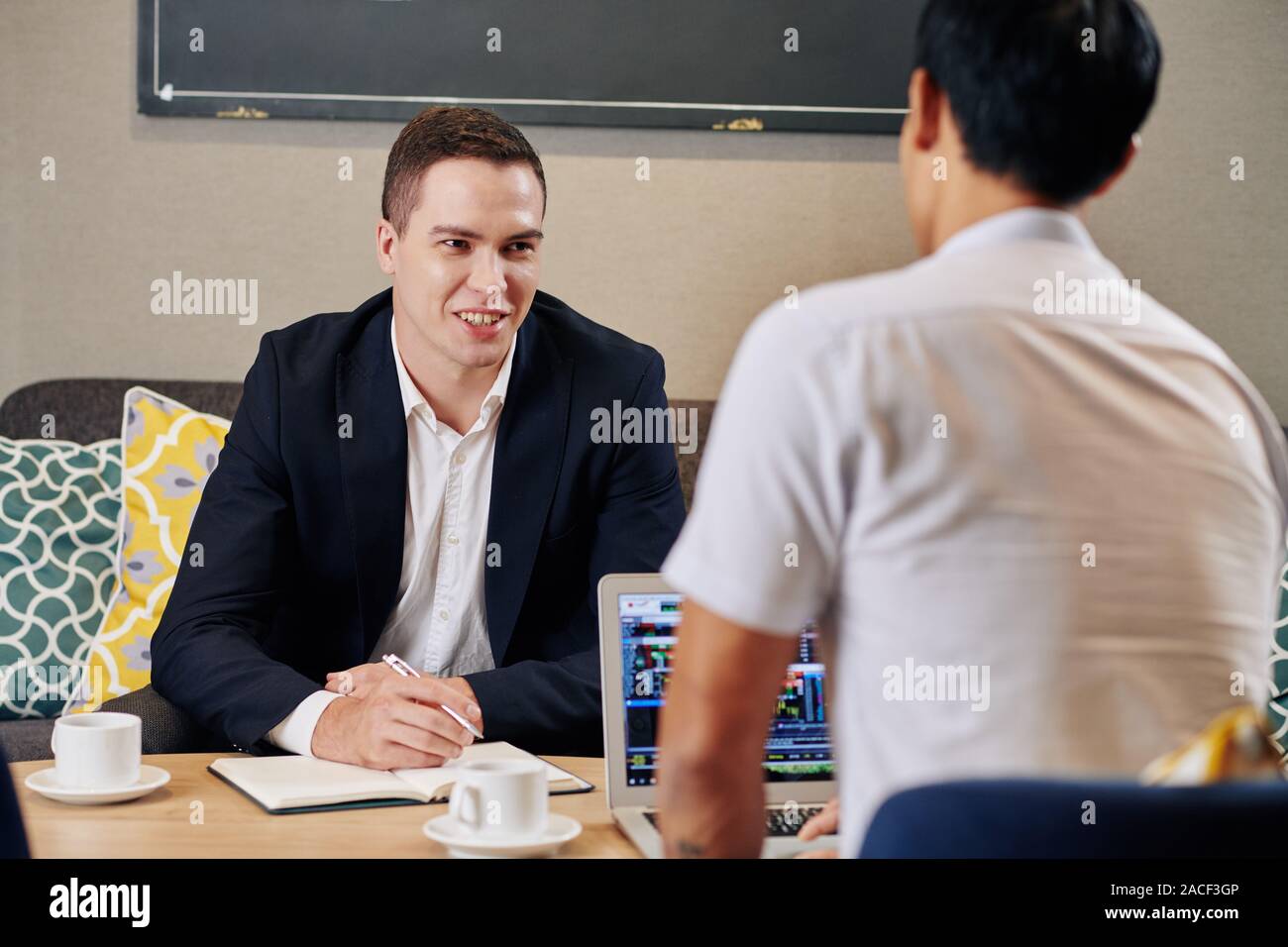 Smiling young entrepreneur listening to his financial adviser and ...