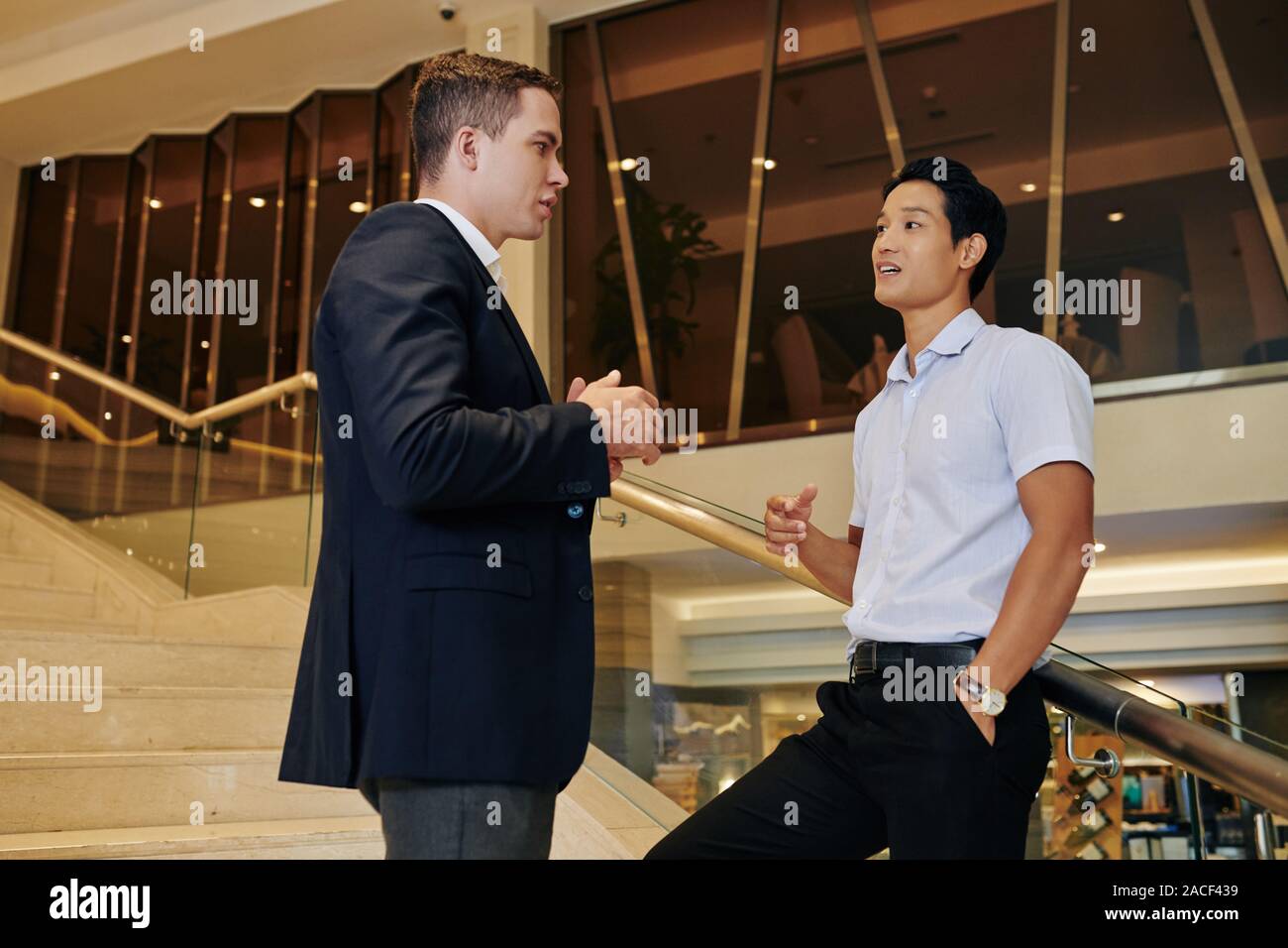 Handsome confident Vietnamese businessman talking to colleague when ...