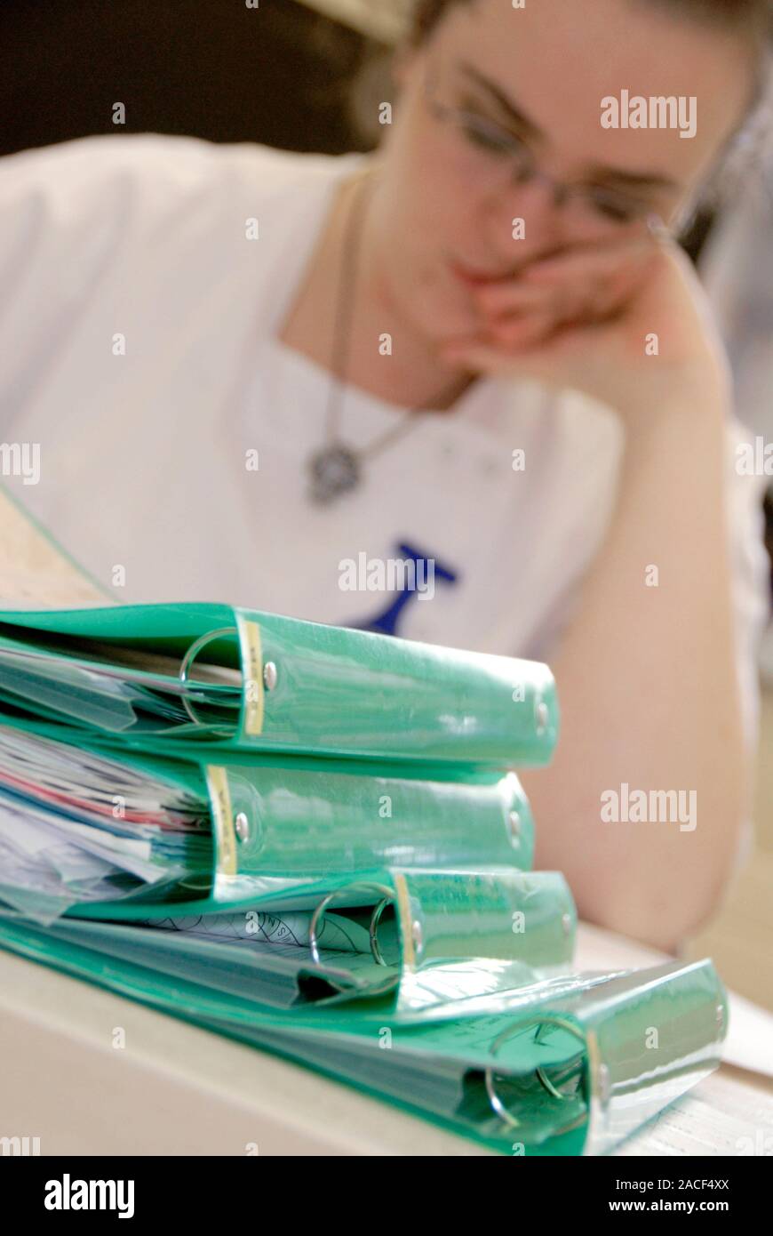 Nurse and hospital records. Nurse at her workstation writing up patient ...