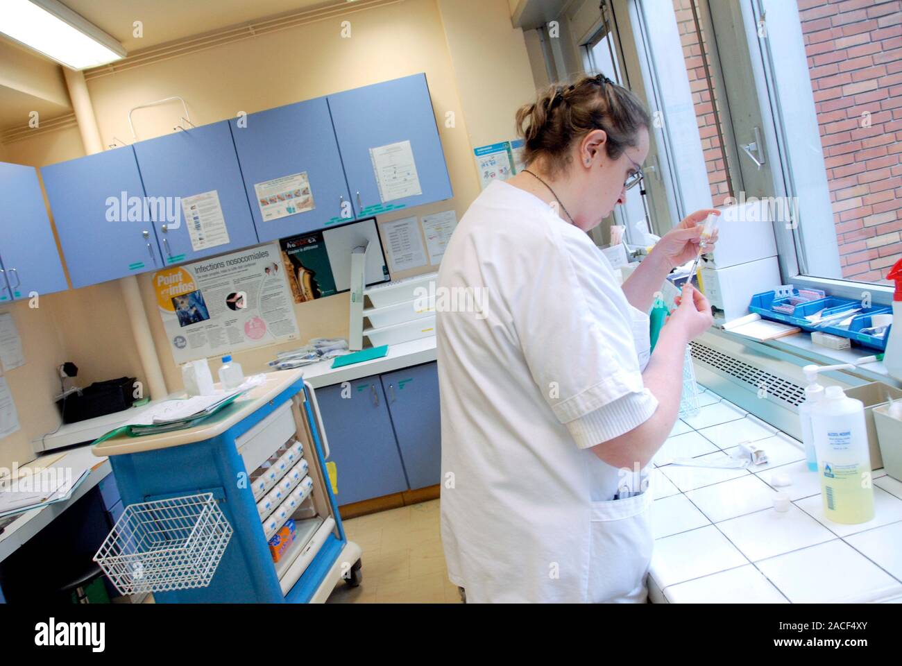 Nurse preparing drugs. Hospital nurse at her workstation preparing a ...
