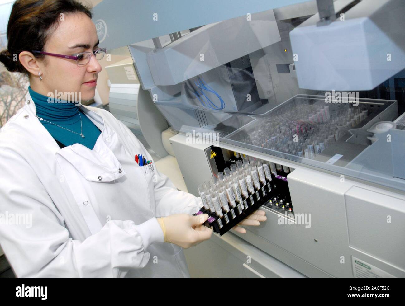 Blood analysis. Haematologist loading samples of donated blood into a ...