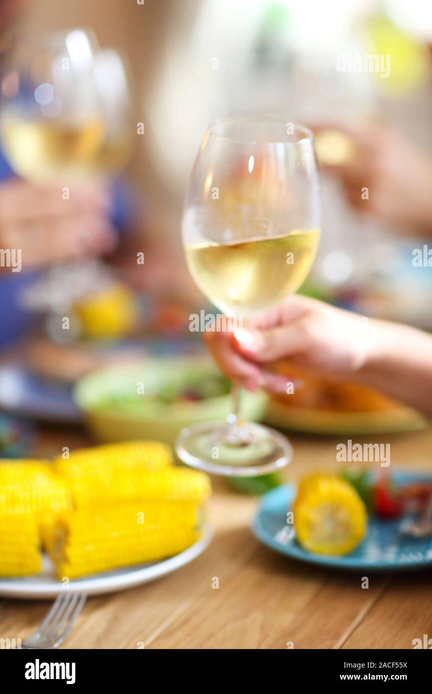 Hands of a group of people cheering with white wine and rising glasses ...