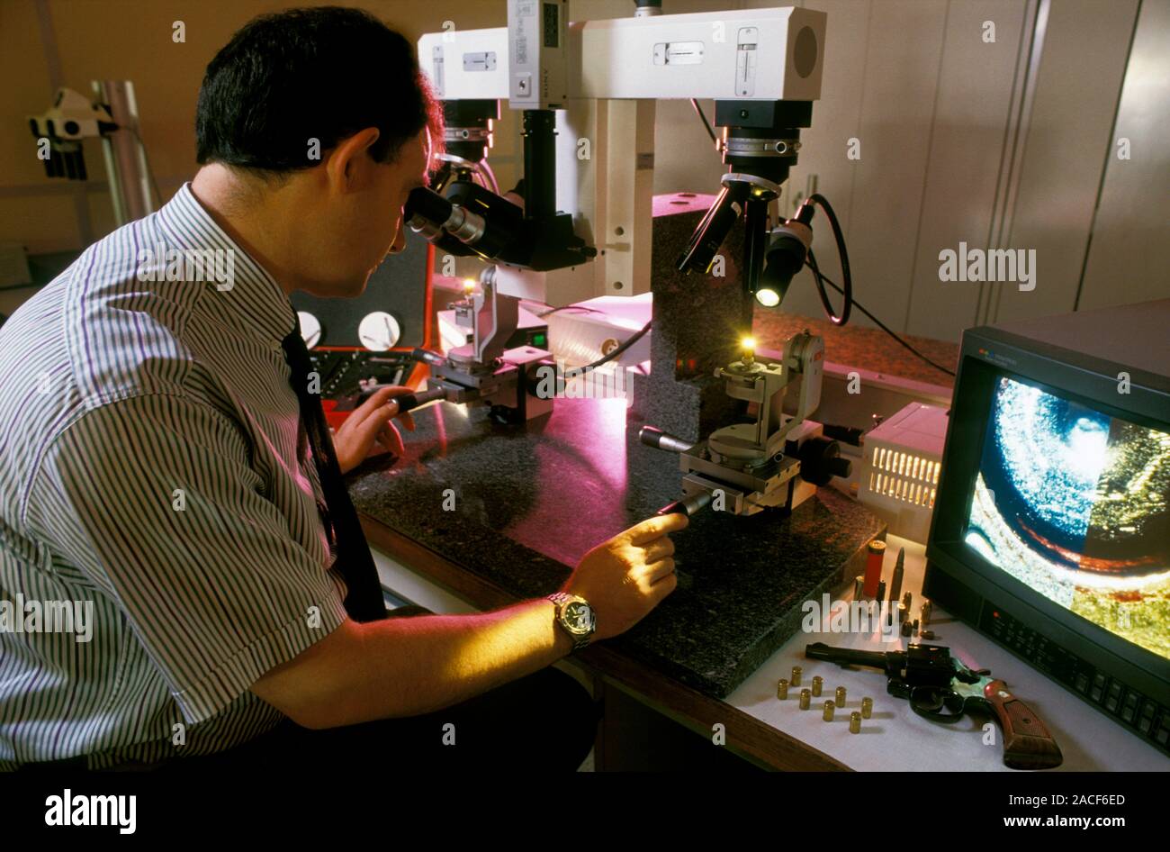 Forensic ballistics cartridge test. Forensic scientist using a ...