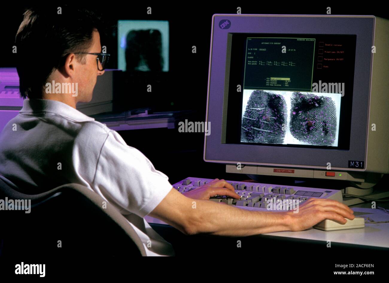 Fingerprint analysis. Forensic scientist using a computer to compare ...